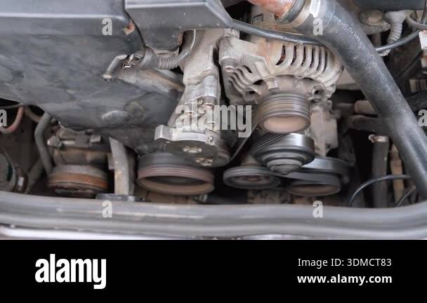 Close up view of a car engine's serpentine belt rotating on pulleys ...
