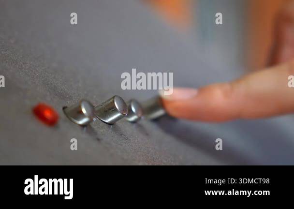 Close-up of a woman's hand pressing a row of metal buttons on a grey ...