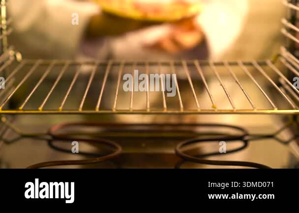 Professional chef carefully placing an uncooked pizza onto the oven ...