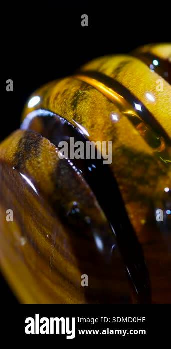 Macro honey dipper dripping golden honey, closeup of amber viscous ...