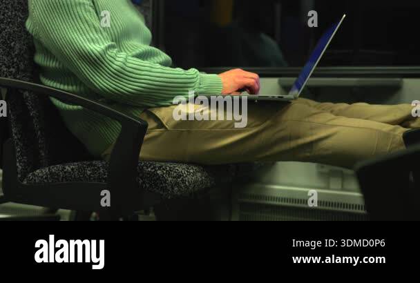 Commuter Typing Laptop On Lap In Dim Train Carriage, Green Sweater And ...