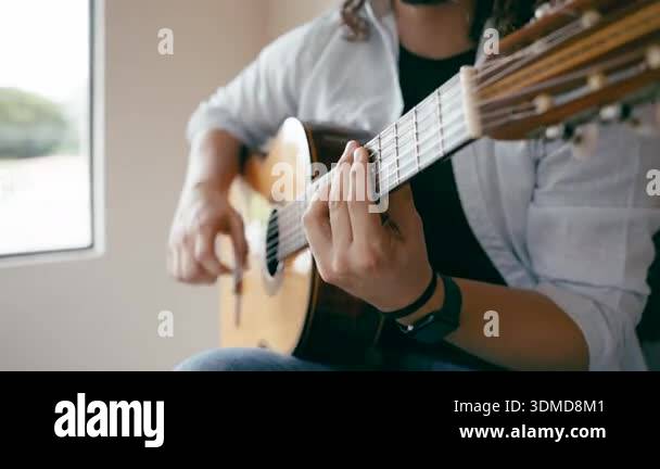 Young man with long hair practicing chords on a classical acoustic ...