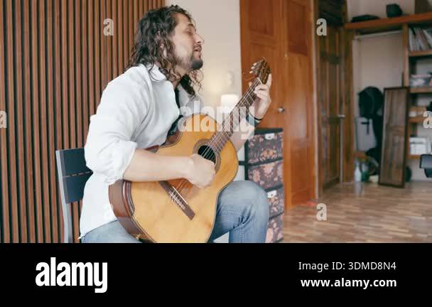 Talented musician with long curly hair passionately singing and playing ...