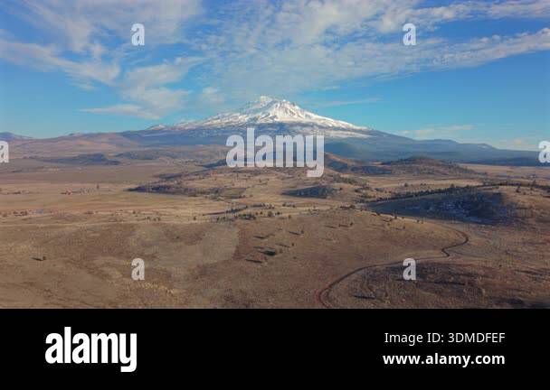 Wide cinematic view of a snow capped Mount Shasta rising above a vast ...