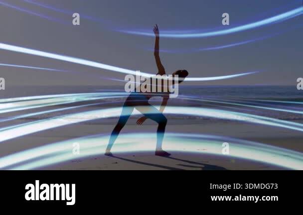 woman holding side angle pose at beach sunrise activating light waves ...