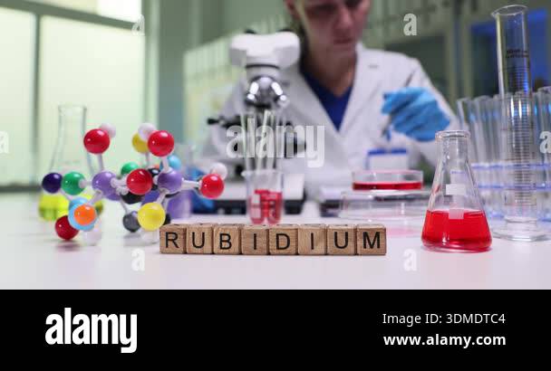 Wooden cubes spell word Rubidium in bright science lab. Female ...