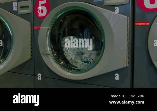 Washing machine in a self-service laundromat displays clothes agitating ...