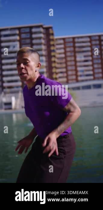 Expressive non binary person with a shaved head and tattoos dancing hip ...