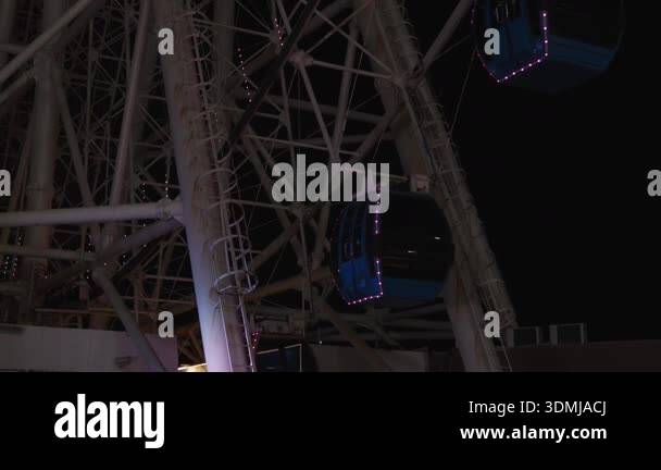 Glowing amusement park observation wheel cabins moving up and down ...