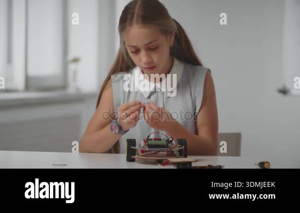 Ingenious schoolgirl designing model bot car at desktop in modern ...