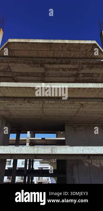 A multi-level concrete building takes shape against a vibrant blue sky ...