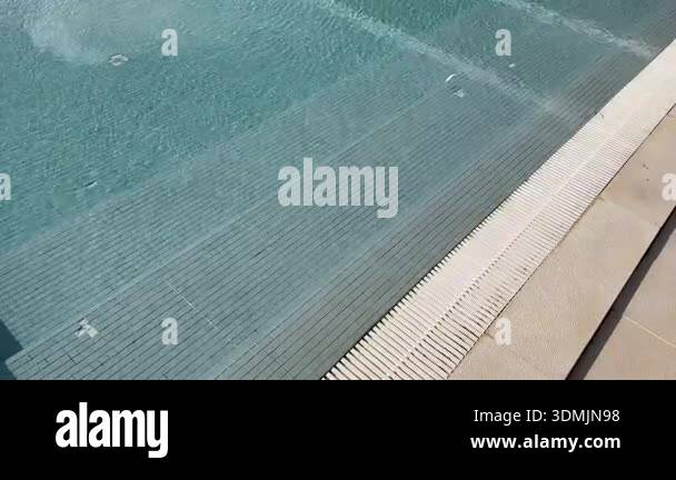 White stone edge of pool and blue pool water texture. Top view, copy ...