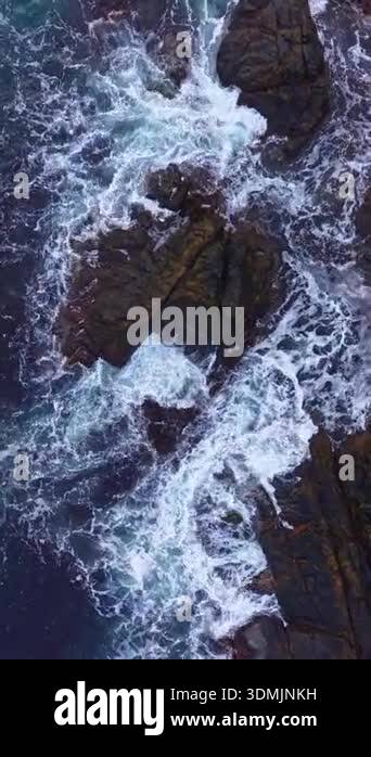 Nature's power unfolds as waves smash onto rugged rocks, sending sprays ...