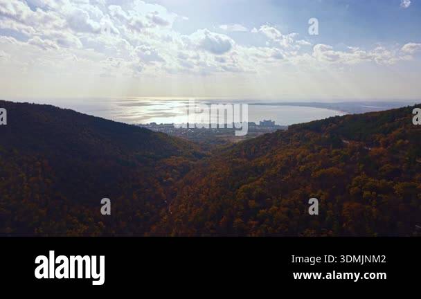Golden sunlight filters through clouds, illuminating a serene coastal ...