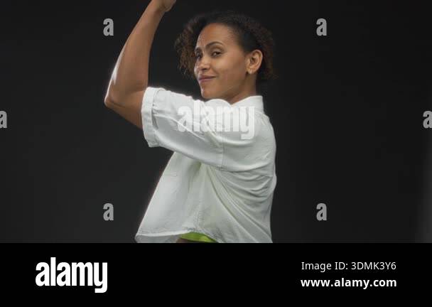 Woman flexes arm showing biceps and clenches fist in studio against ...