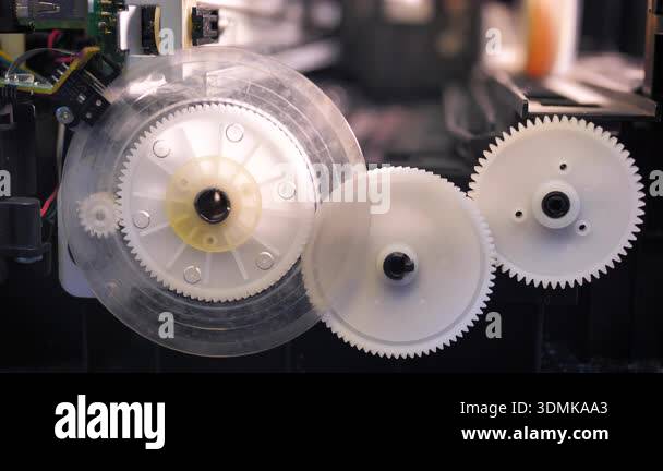 Close-up of rotating printer gears inside a mechanical system, showing ...