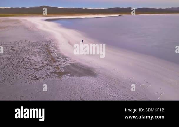 A solitary man walks across the vast, reflective salt flats of Salinas ...