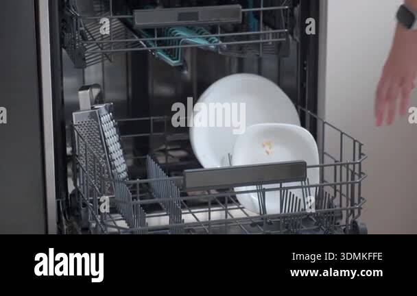 Woman loading modern dishwasher with dirty dishes. Person placing used ...