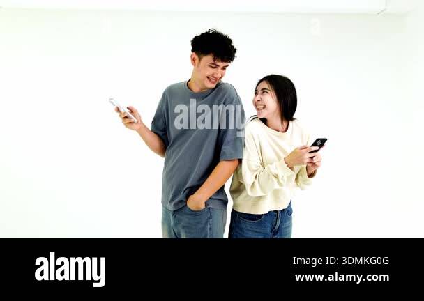 Two people stand back-to-back, each absorbed in their smartphone. Set ...