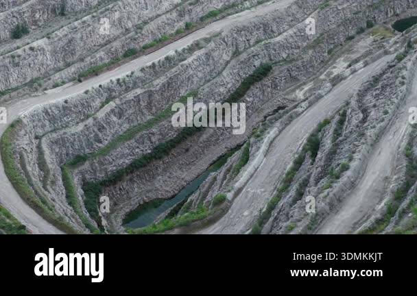 Quarry exposing deep terraced rock layers with narrow water channels ...