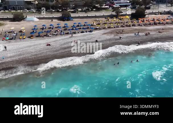 Waves break on the shore of a beautiful Rodos Greece beach. People swim ...