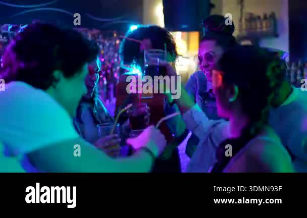 Group of multi ethnic friends dancing, drinking cocktails, and toasting ...