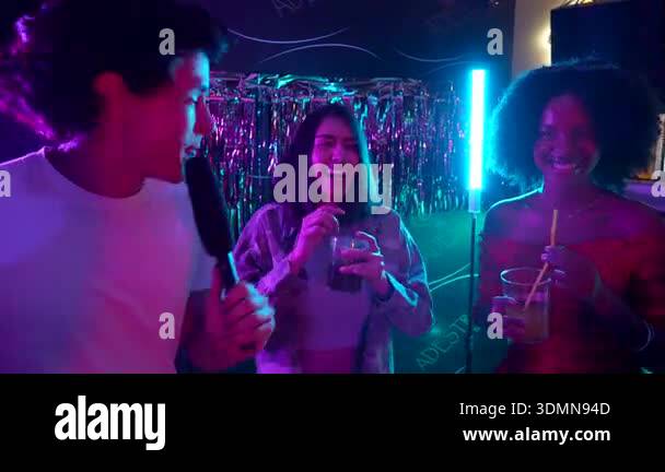 Diverse young friends laughing and singing karaoke in a vibrant ...
