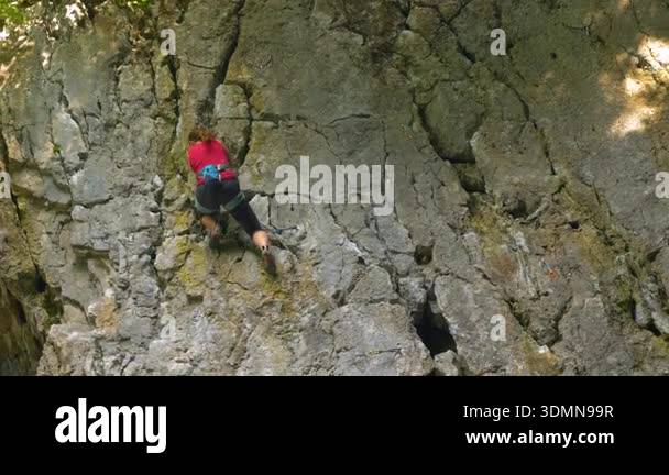 Fit female rock climber taking on the challenging limestone cliff on a ...