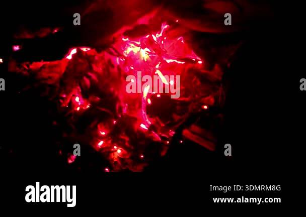 Macro video of red hot coals and glowing embers in darkness, creating a ...