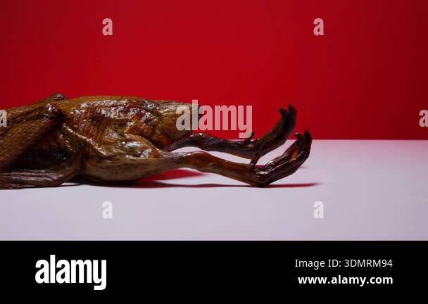 Whole roasted glazed duck with head and feet attached resting on a ...