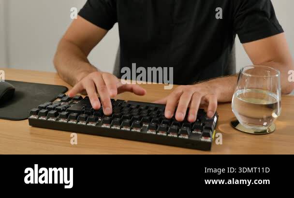 Man typing on mechanical keyboard at desk, close-up of hands working on ...