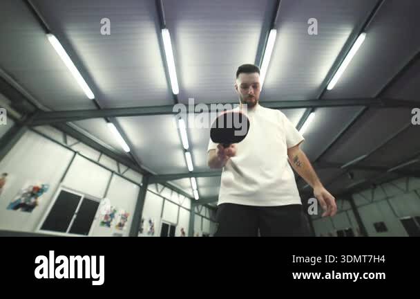 Young male athlete practicing table tennis skills by bouncing a ball on ...