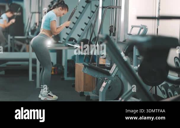 Athletic woman exercising her triceps using a cable machine during an ...