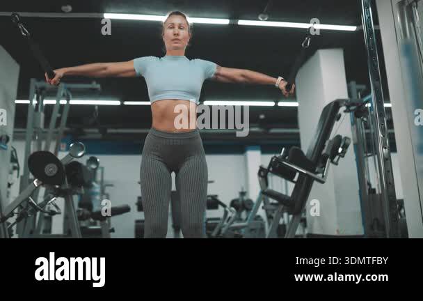 Strong woman working out her chest and shoulder muscles on a cable ...