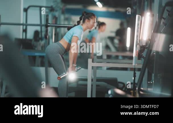Young athletic woman performing dumbbell romanian deadlifts in a modern ...