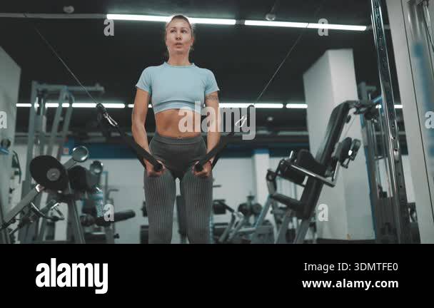 Fit caucasian woman working out her pectoral muscles on a cable ...