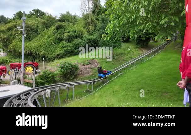 roller coaster moving along rails on a green hillside in a park. Scenic ...