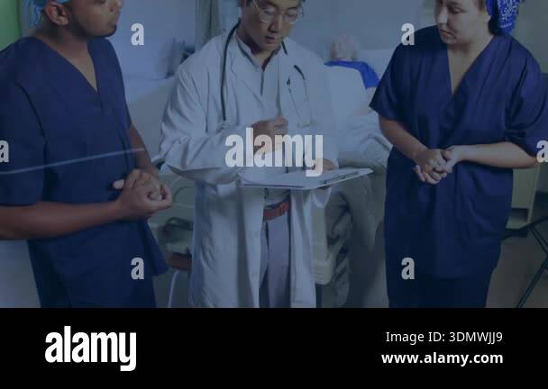 Doctor reviewing clipboard guiding nurses at patient bed in hospital ...