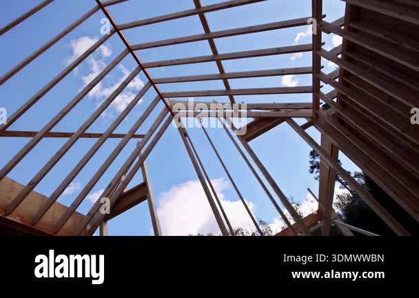 Workers build roof trusses rafters using wooden beams under roofing ...