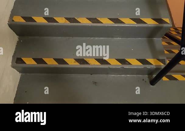 Camera tilts up showing gray stairs going up with yellow black safety ...
