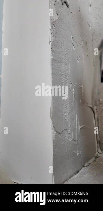A worker spreads plaster on the walls of a room during a home ...