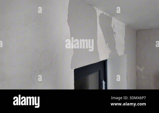 A person is repairing a wall by applying plaster to cover damaged areas ...
