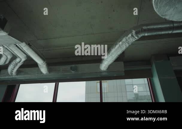 Several industrial metal air ducts and ventilation pipes are mounted to ...