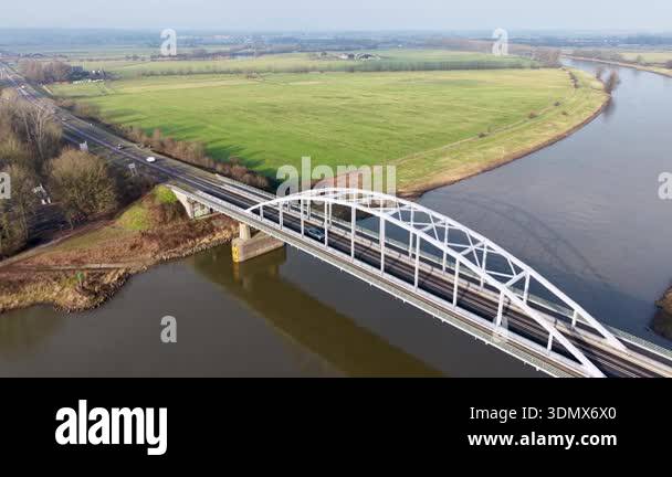 Aerial view of arched highway bridge over curving river, linking green ...