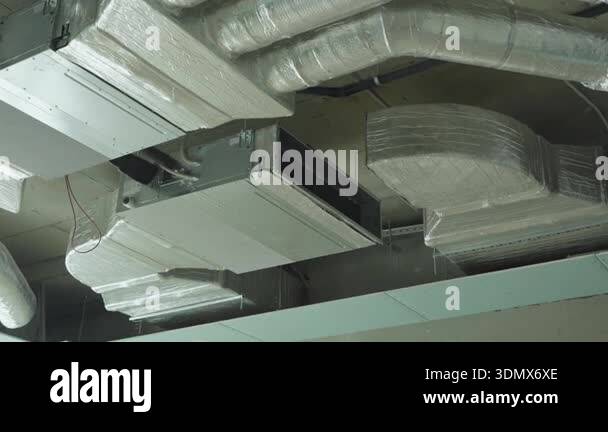 Several industrial metal air ducts and ventilation pipes are mounted to ...