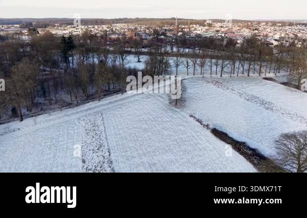 Snowy rural landscape with open fields scattered leafless trees and ...
