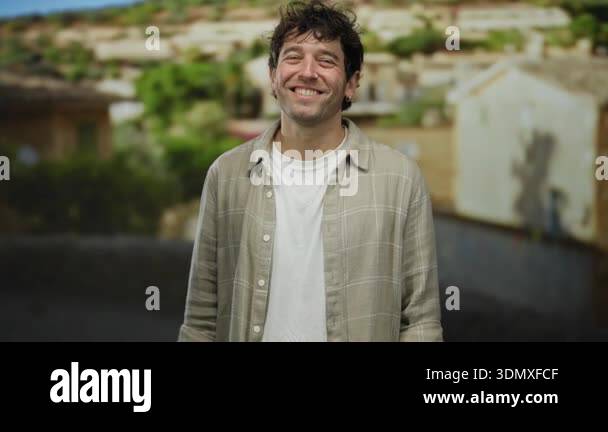 Hispanic man smiling in a charming mediterranean town, wearing casual ...