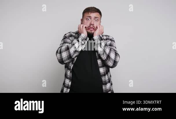 A man stands in a studio with a shocked expression. He puts his hands ...