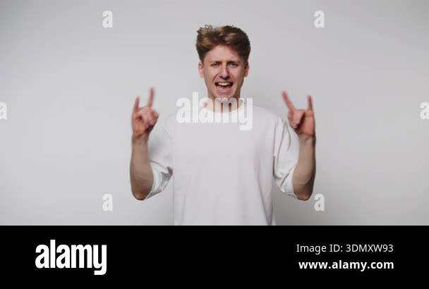 A man stands in front of a plain backdrop showing various hand signs ...