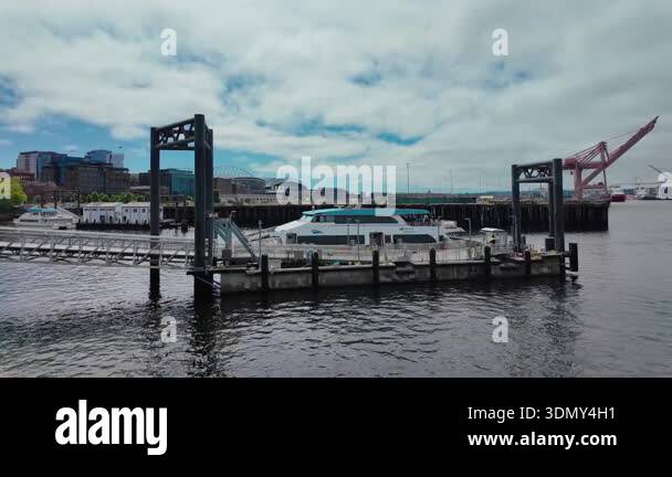 Passenger boat docked at urban waterfront marina with city buildings ...